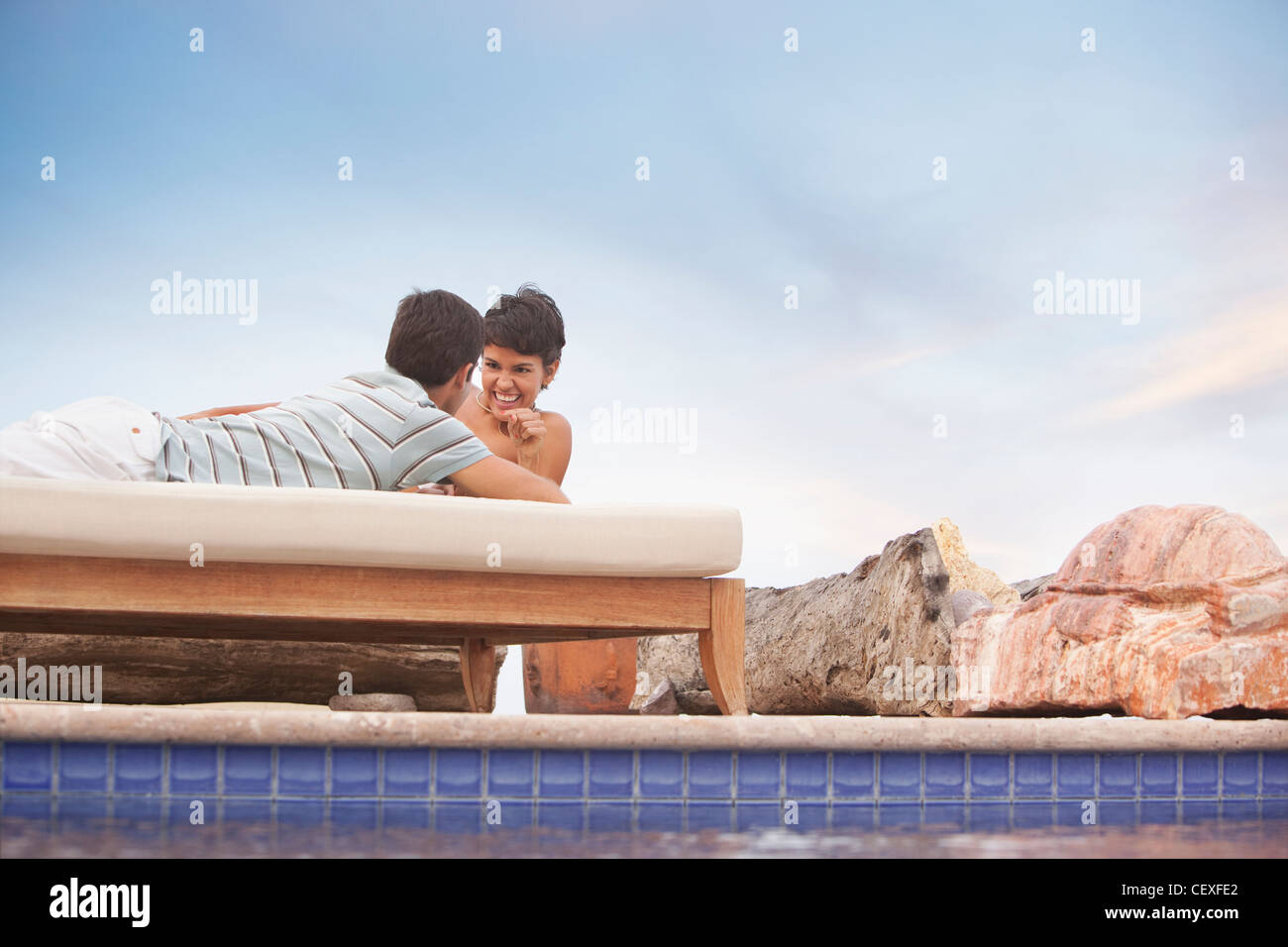 Hispanic couple relaxing at poolside Stock Photo - Alamy