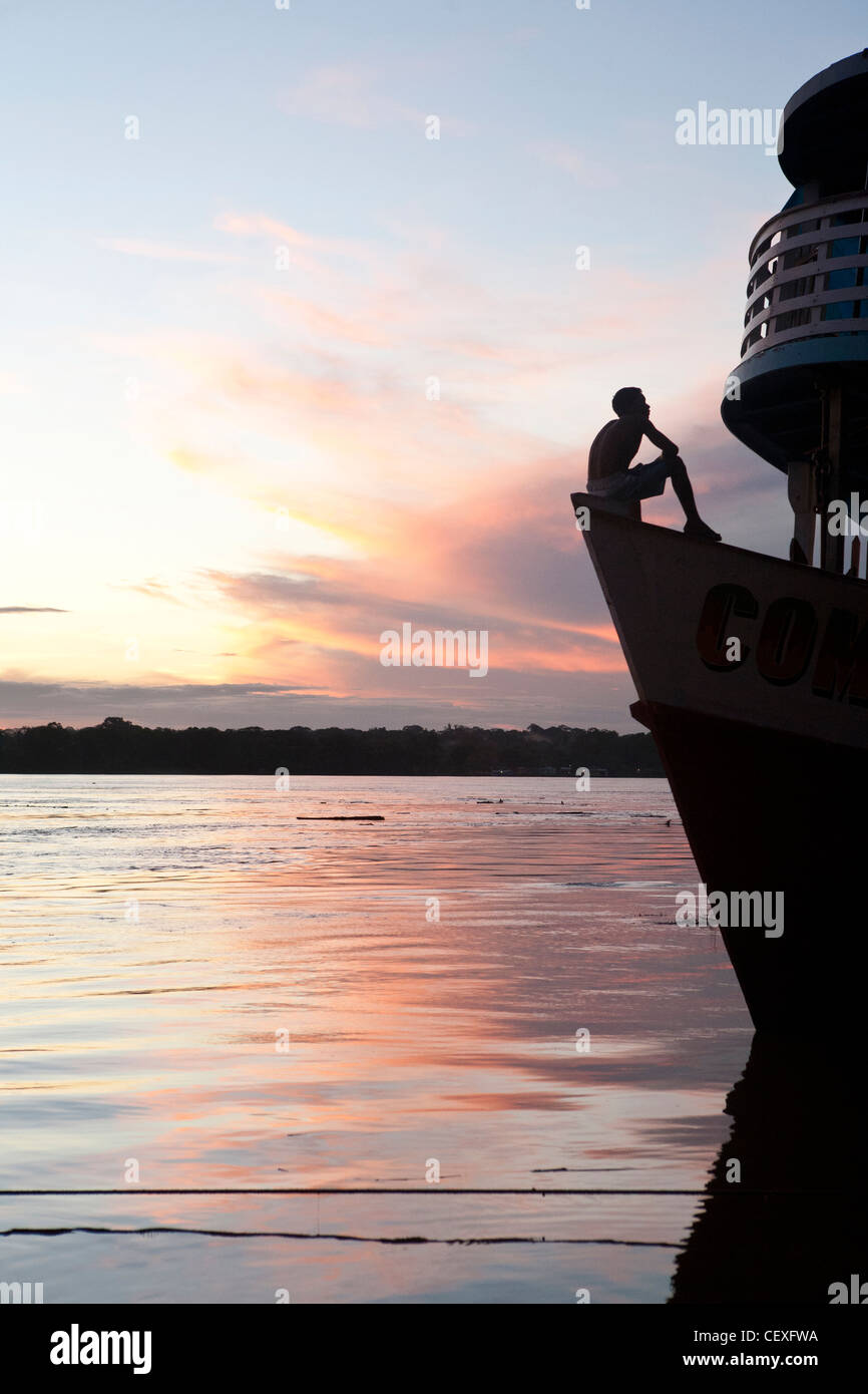 Young man sitting on boat at sunset Stock Photo - Alamy