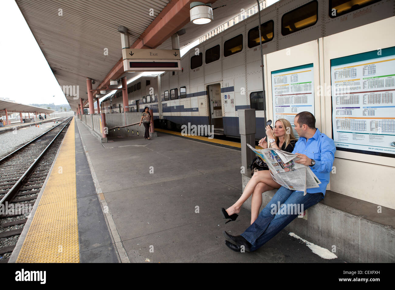Couple sitting on train platform waiting for train Stock Photo - Alamy