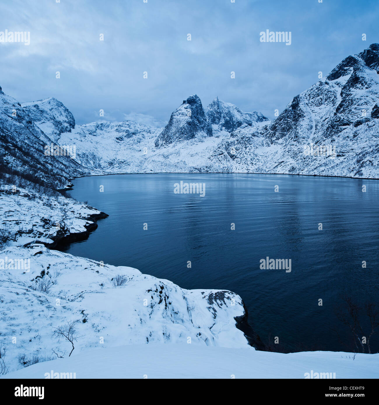 Mountain peaks rise above Djupfjord in winter, Moskenesoy, Lofoten ...