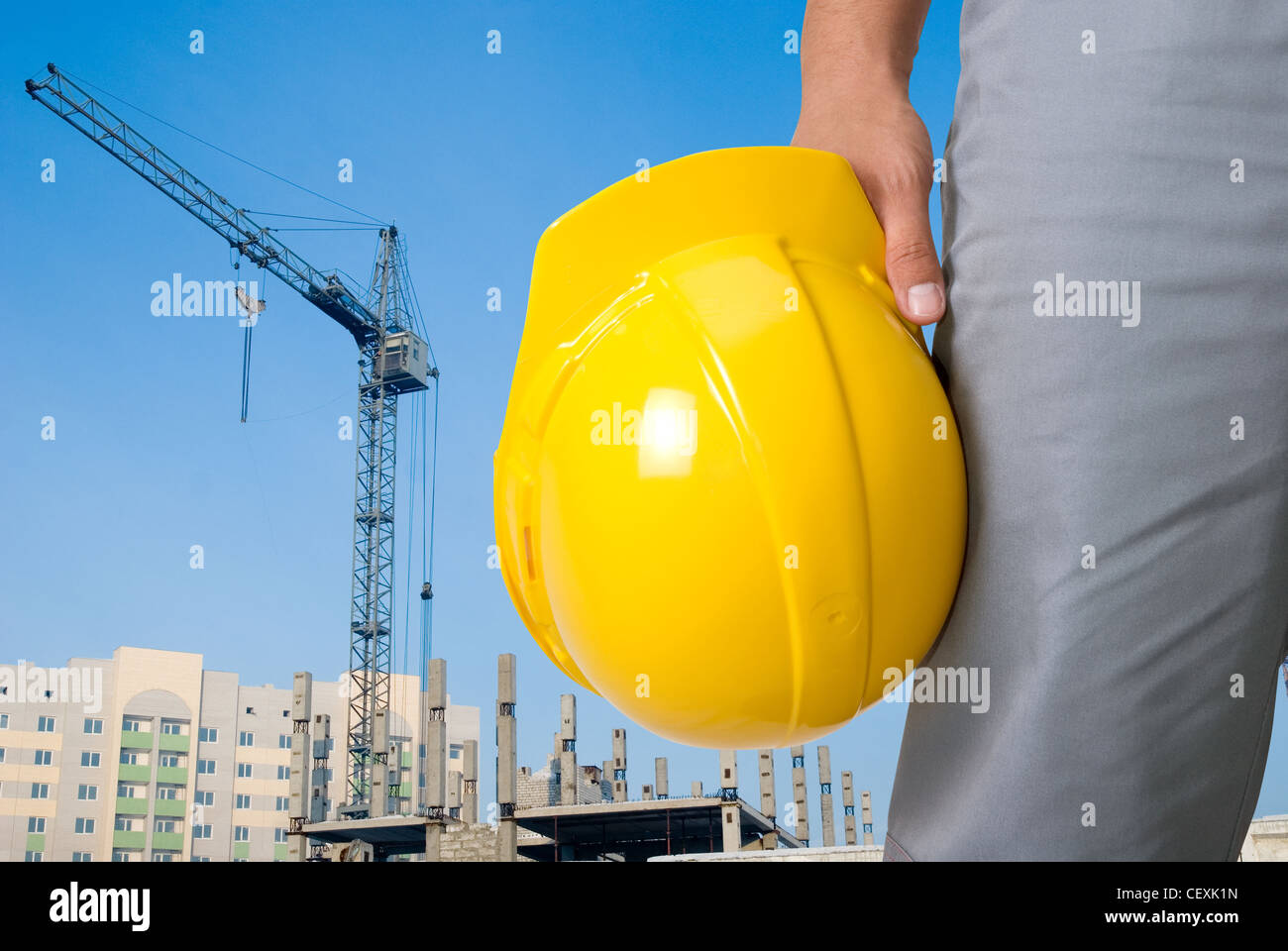 Closeup of builder with yellow helmet on building panorama background ...