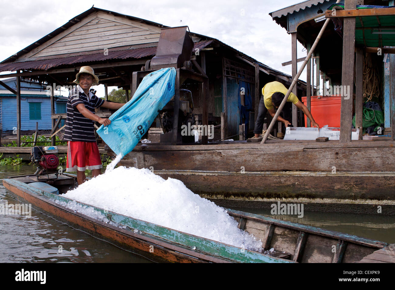 Two men work at a floating ice factory making and crushing ice for use ...