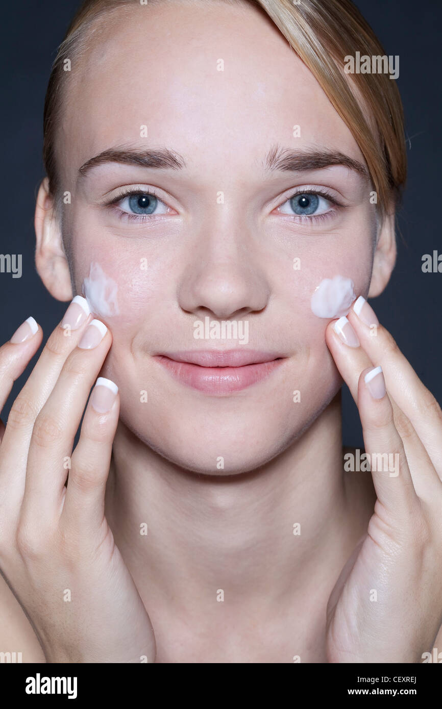 Step by Step Beauty and Make Up Female applying face cream to her cheek ...