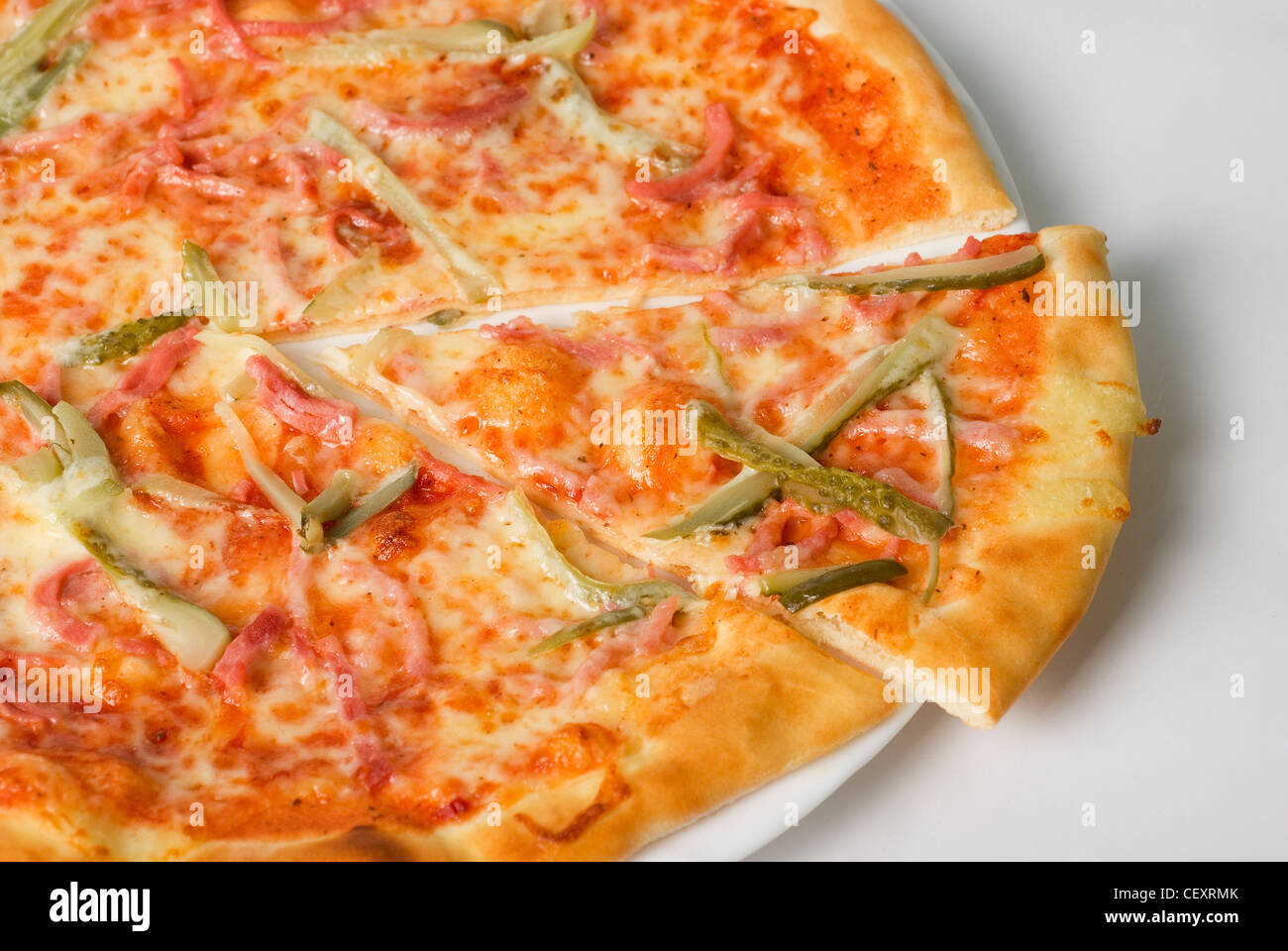 pizza closeup with boiled sausage, ham, marinated gherkin and ...