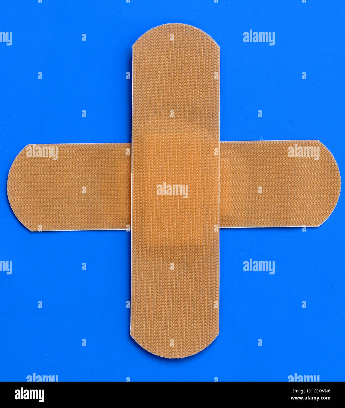 A cross made from two plasters, on a blue background Stock Photo - Alamy