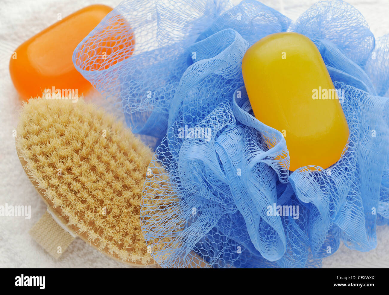 A yellow bar of soap, on a blue nylon mesh shower puff, with a back ...