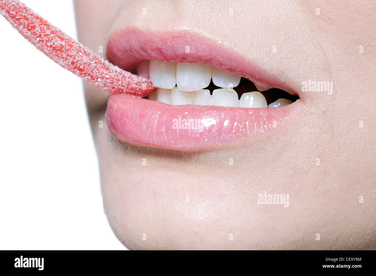 Female wearing pink lipgloss, eating a strawberry lace Stock Photo - Alamy