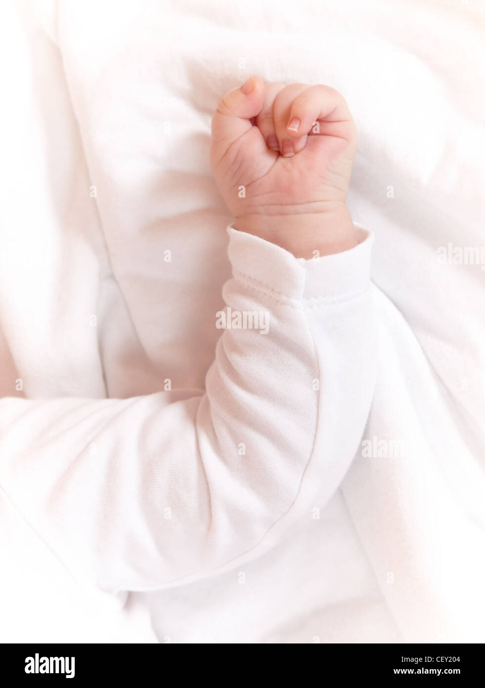 Small hand of a newborn baby dressed in white while sleeping. Close-up ...