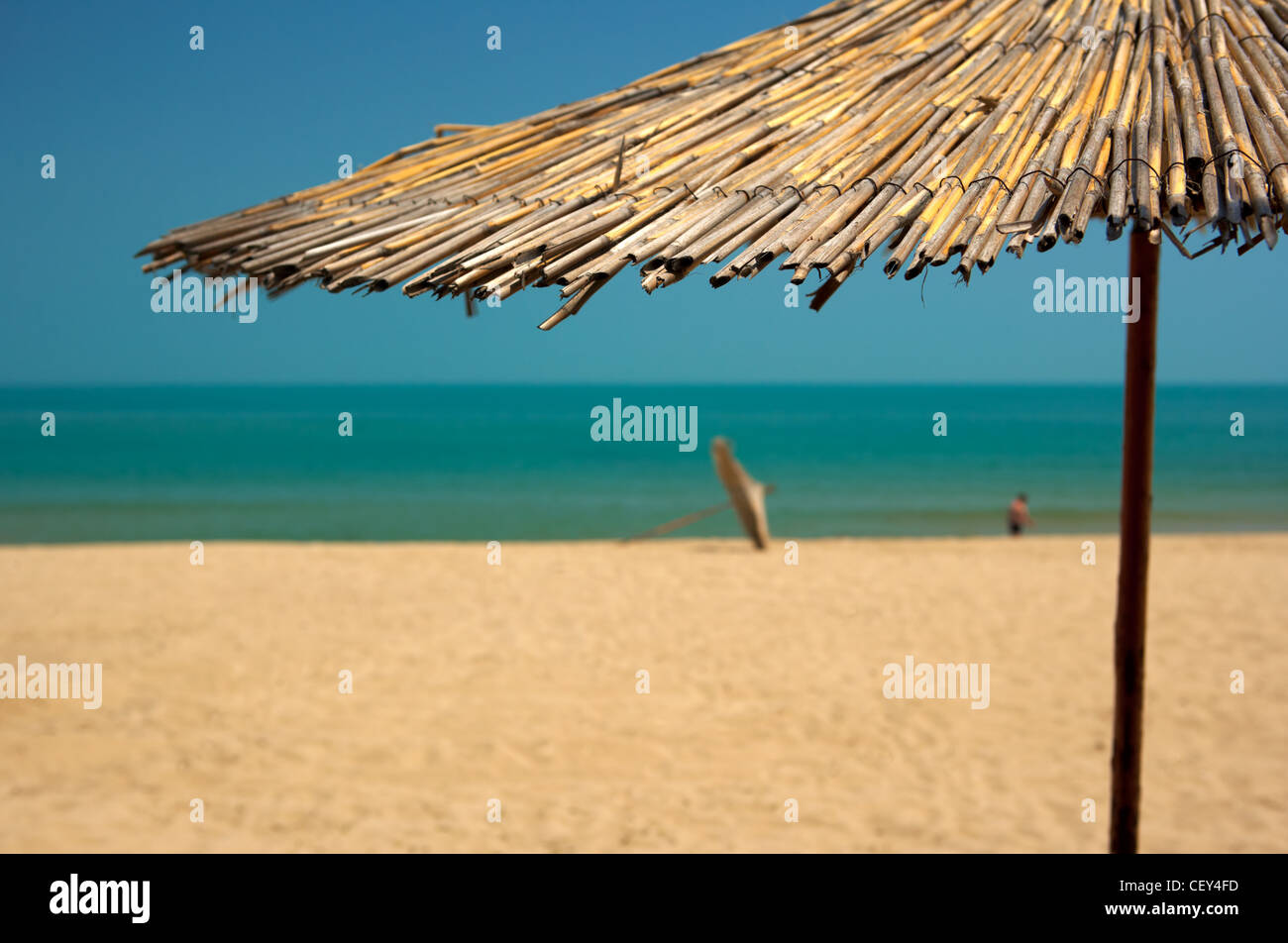 Tropical beach with parasols, blue sea water and golden sands Stock ...