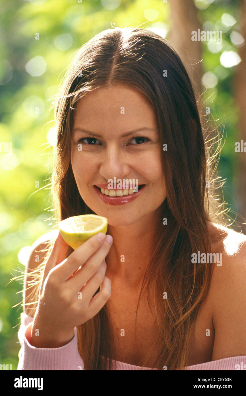 Brunette female straight centre parting hair and glossy lips, eating ...