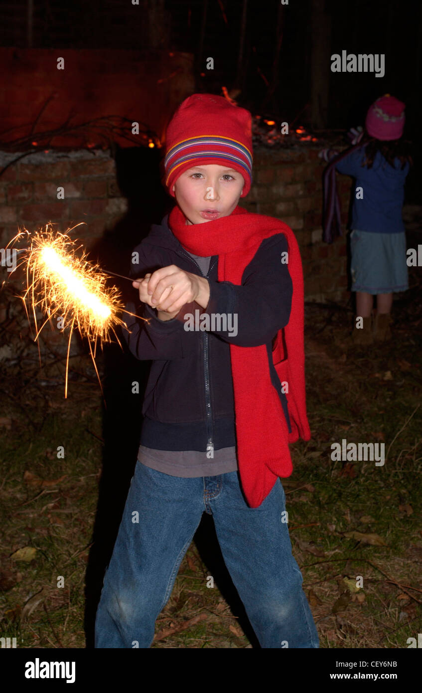 Night time image of male child swinging a sparkler both hands, looking ...