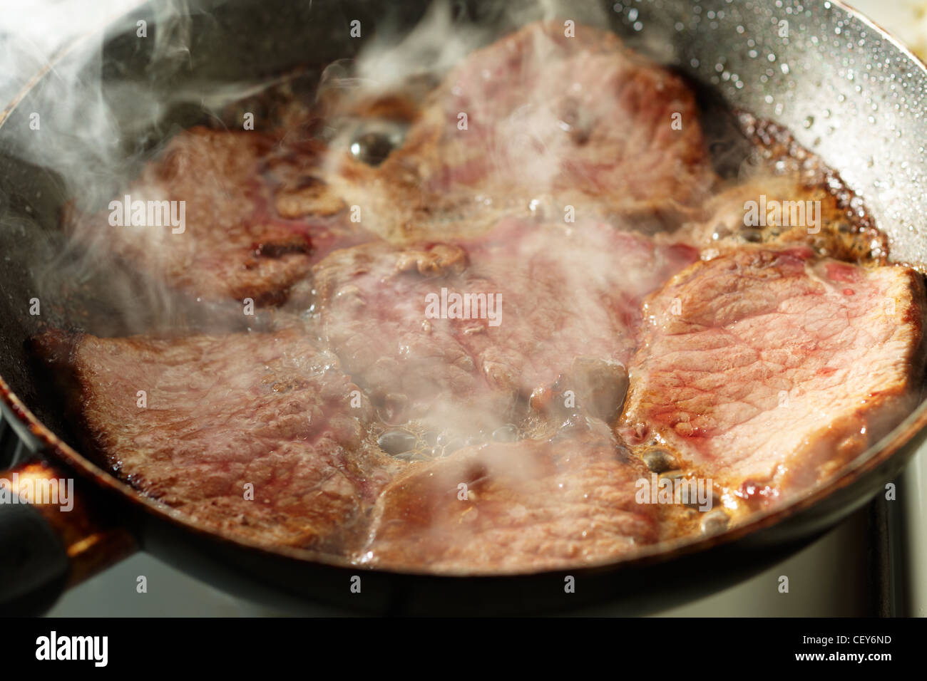 Frying fresh veal fillet in a frying pan and some vapor Stock Photo - Alamy