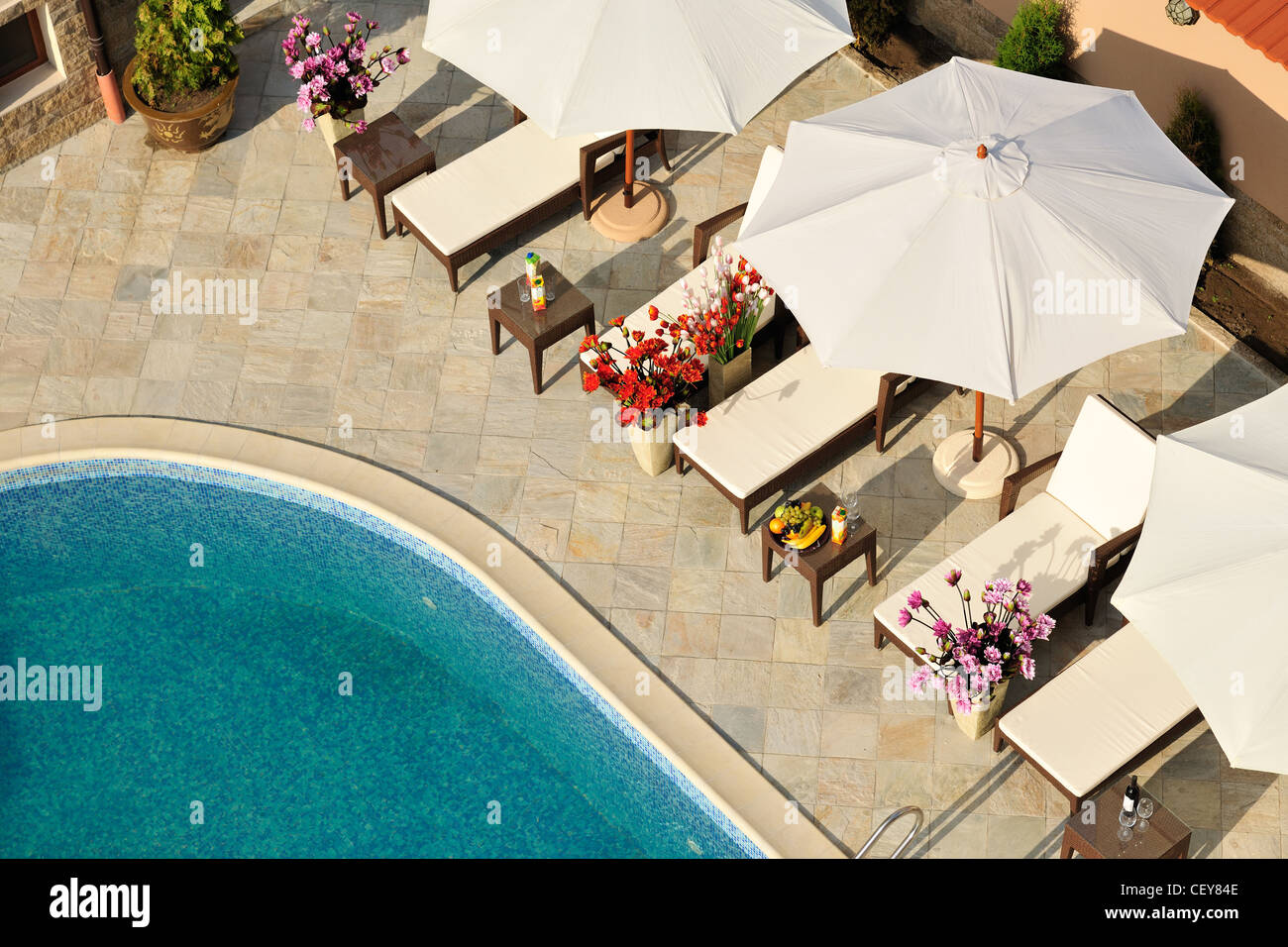 Swimming pool in small hotel yard with parasols and chaise-longues ...