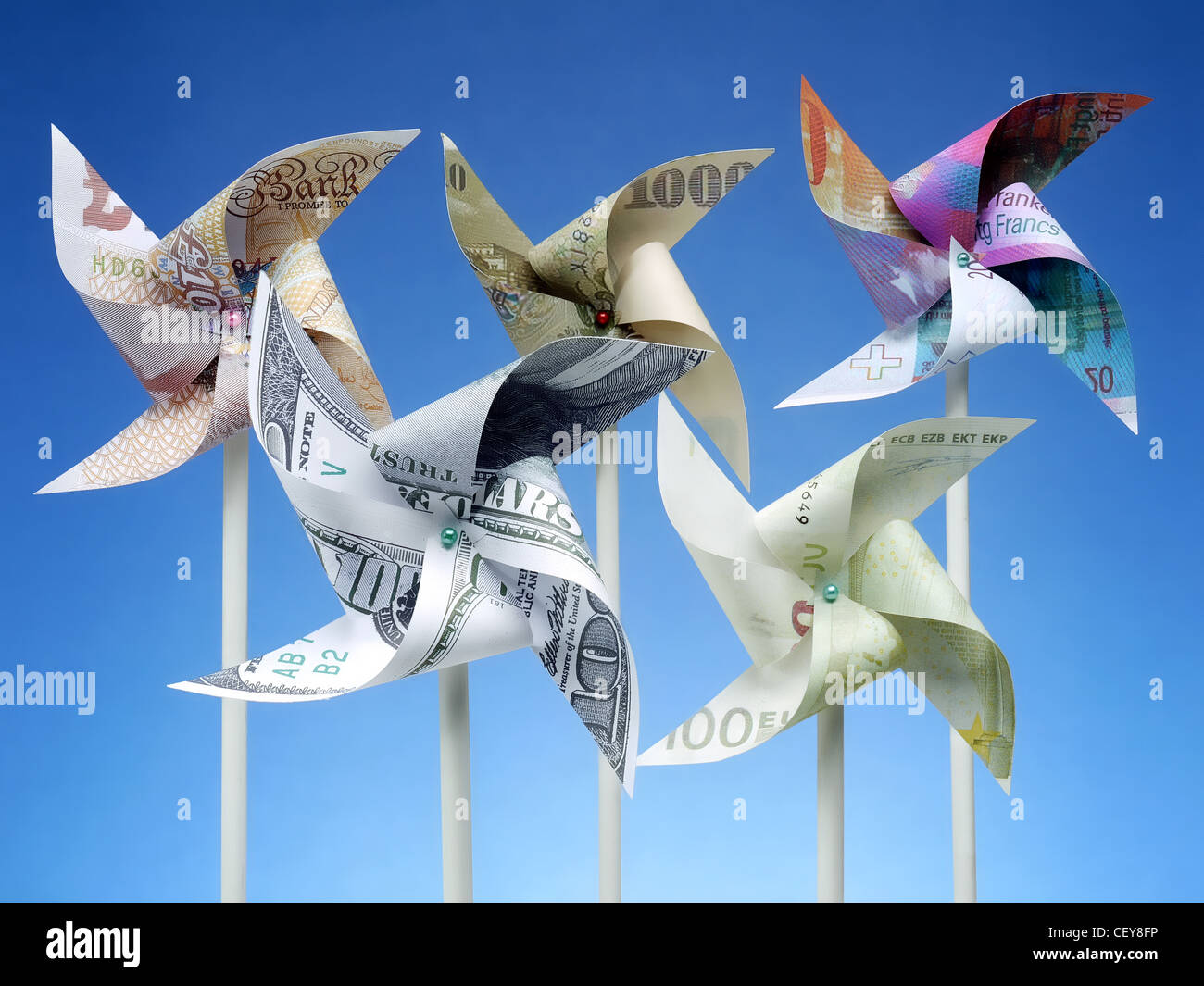 Toy windmills cut from five major world currency banknotes over blue ...