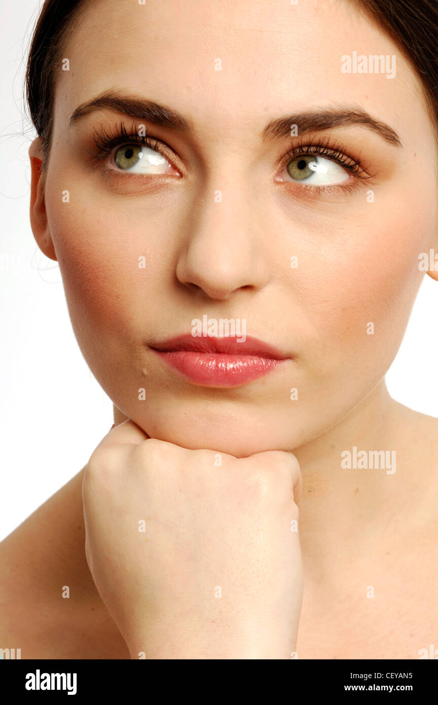 Female with brunette hair off face looking up and to side resting chin ...