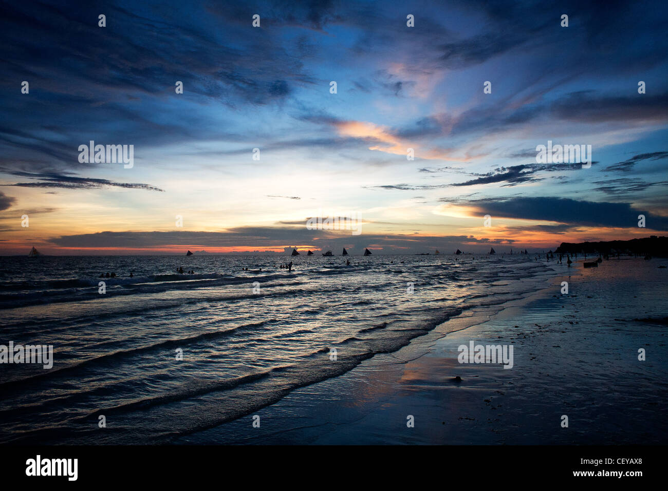 The sun descends behind the clouds and lights the horizon in Boracay ...