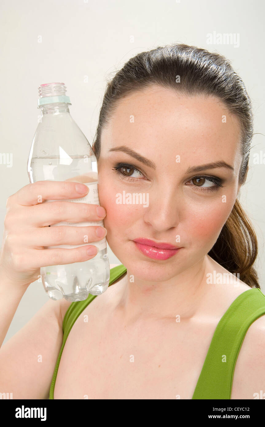 Female holding bottle of water to cheek Stock Photo - Alamy