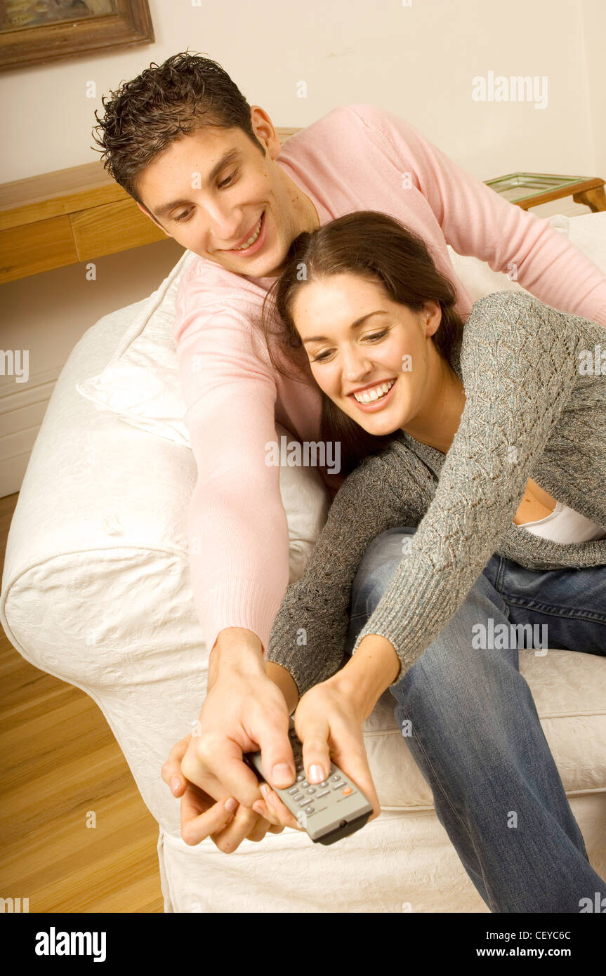 Couple lying on sofa fighting over remote control Stock Photo - Alamy