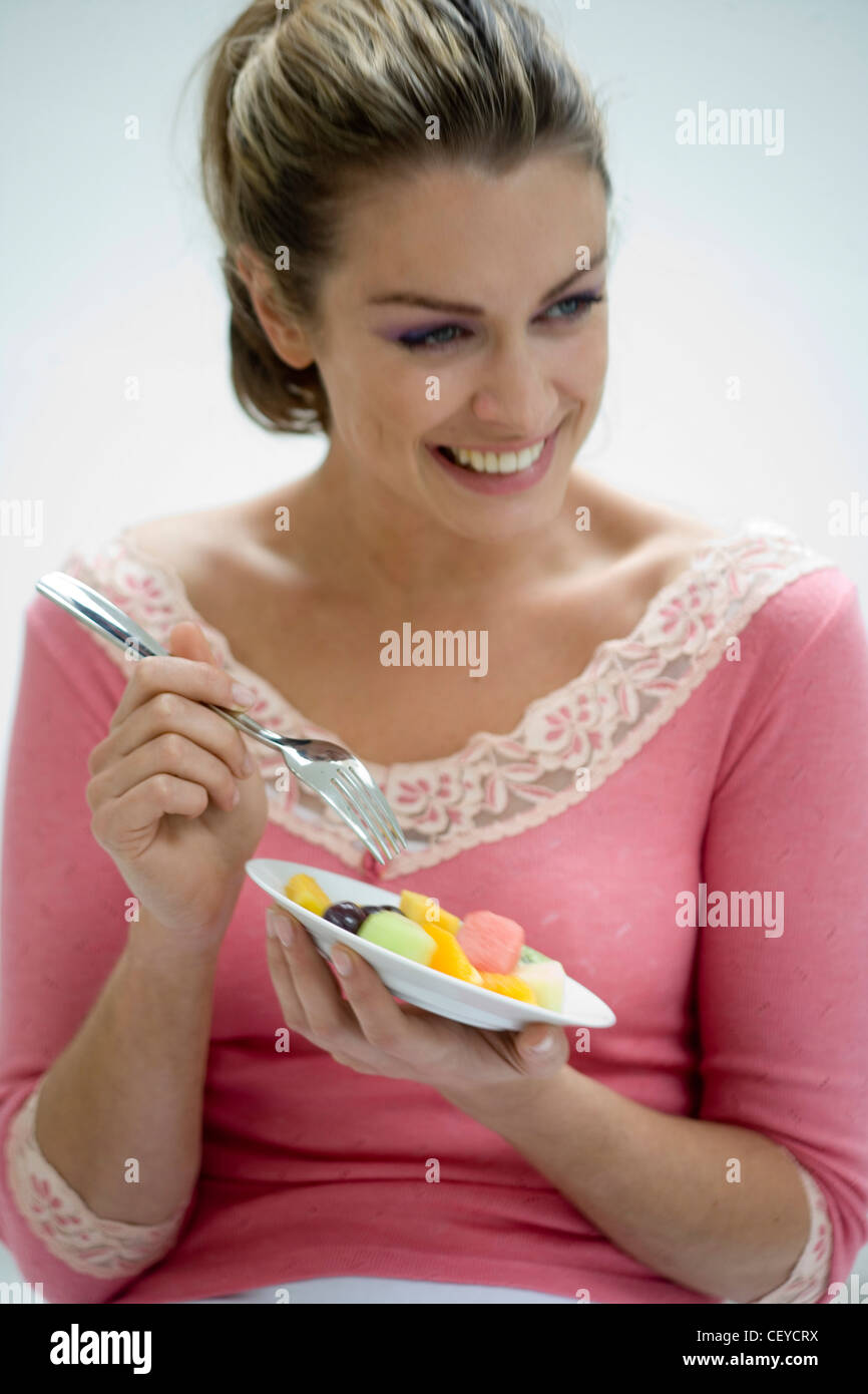 Female eating a plate of fruit salad Stock Photo - Alamy
