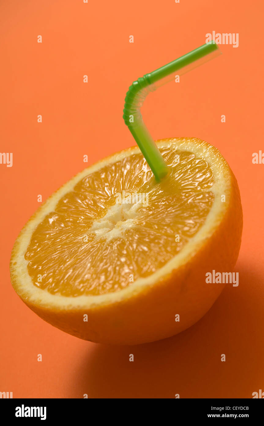 Half an orange with a straw stuck in it, on an orange background Stock ...