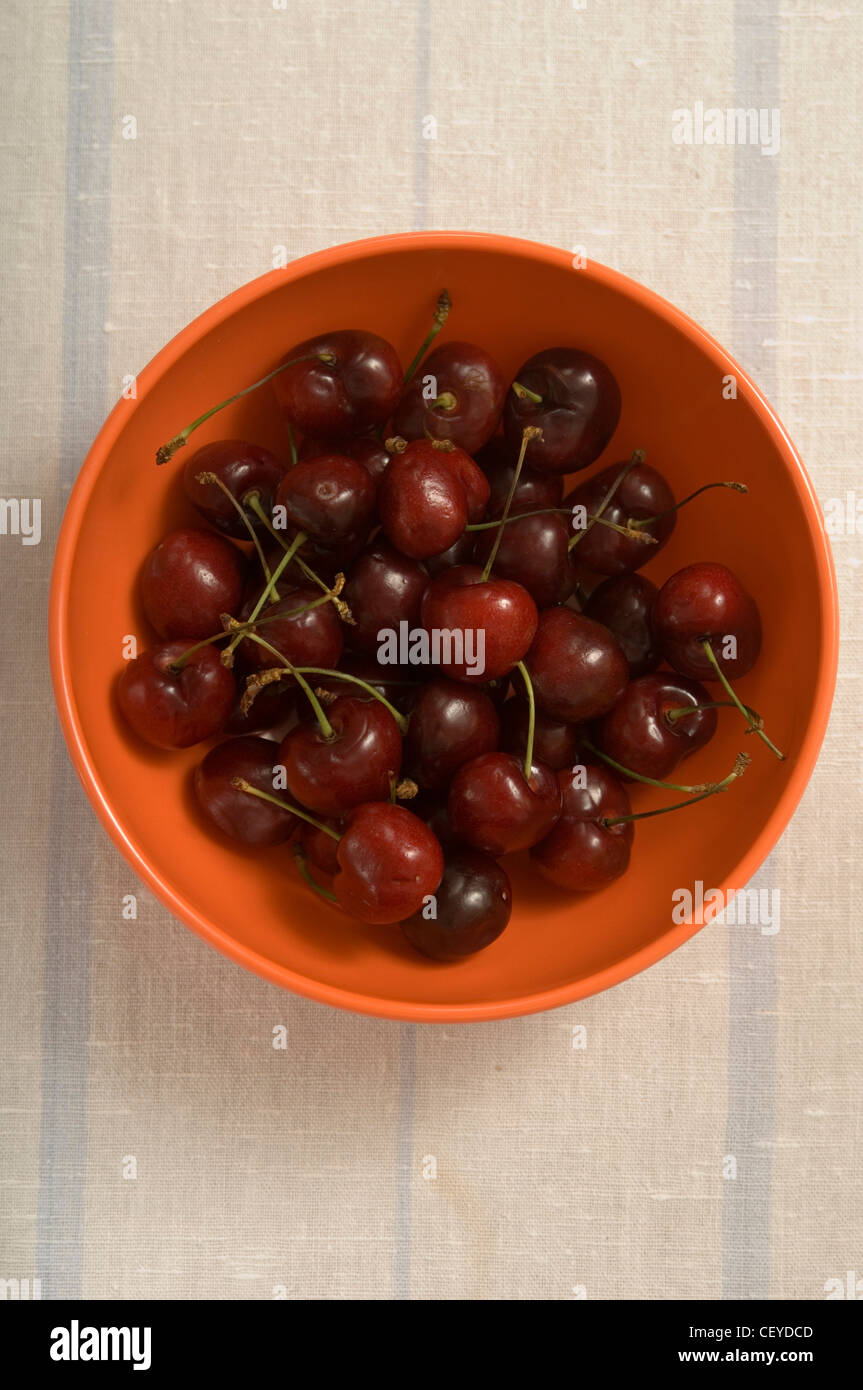 Red cherries in an orange bowl on a white background Stock Photo - Alamy