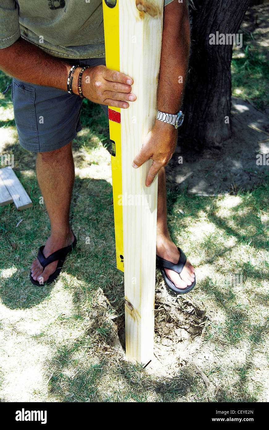 FORBuild a Tree House Step Male aligning a plank of wood using a spirit ...