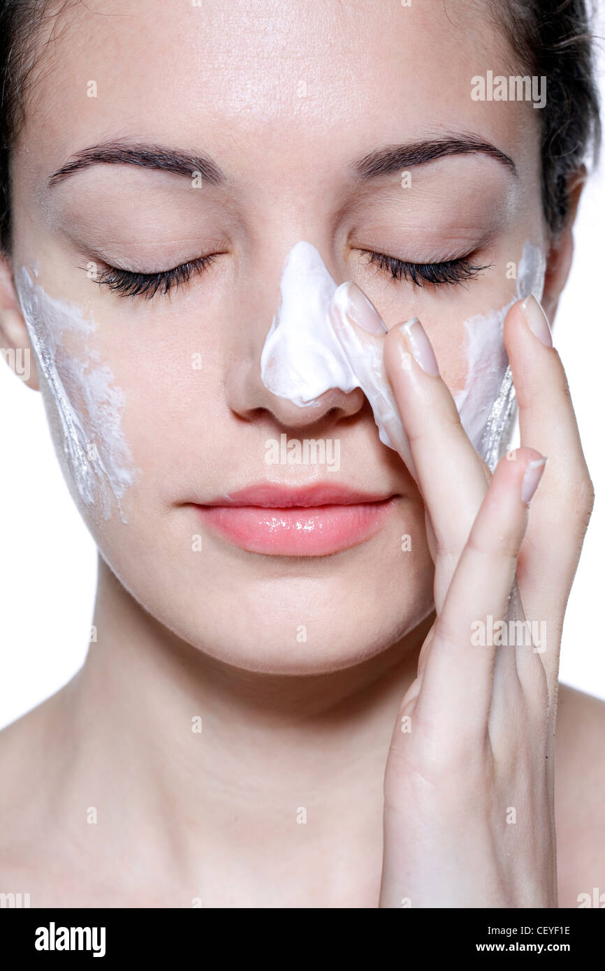 Female brunette hair off her face, applying face cream to her nose the ...