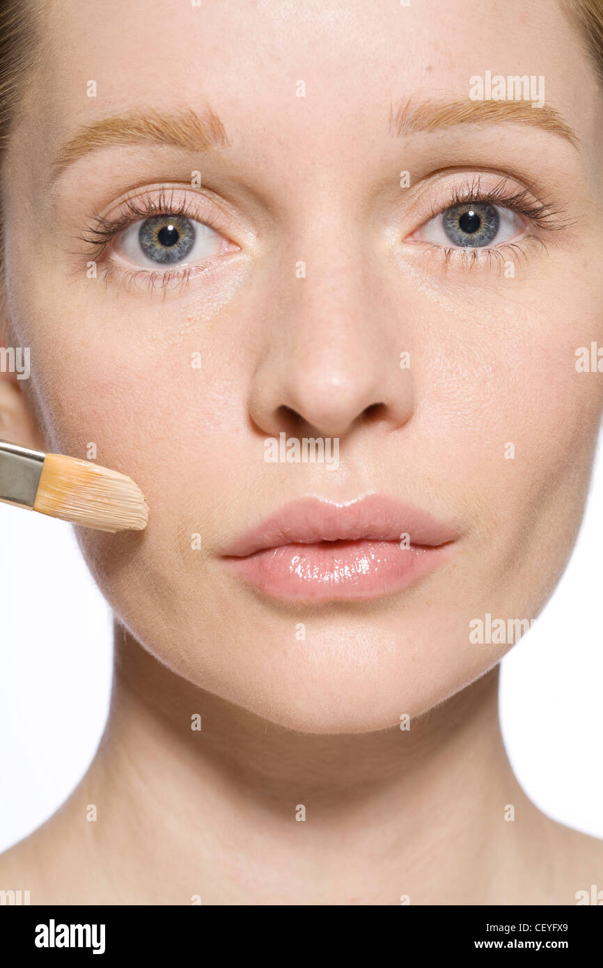 Female fair hair off her face, wearing minimal make up, applying ...