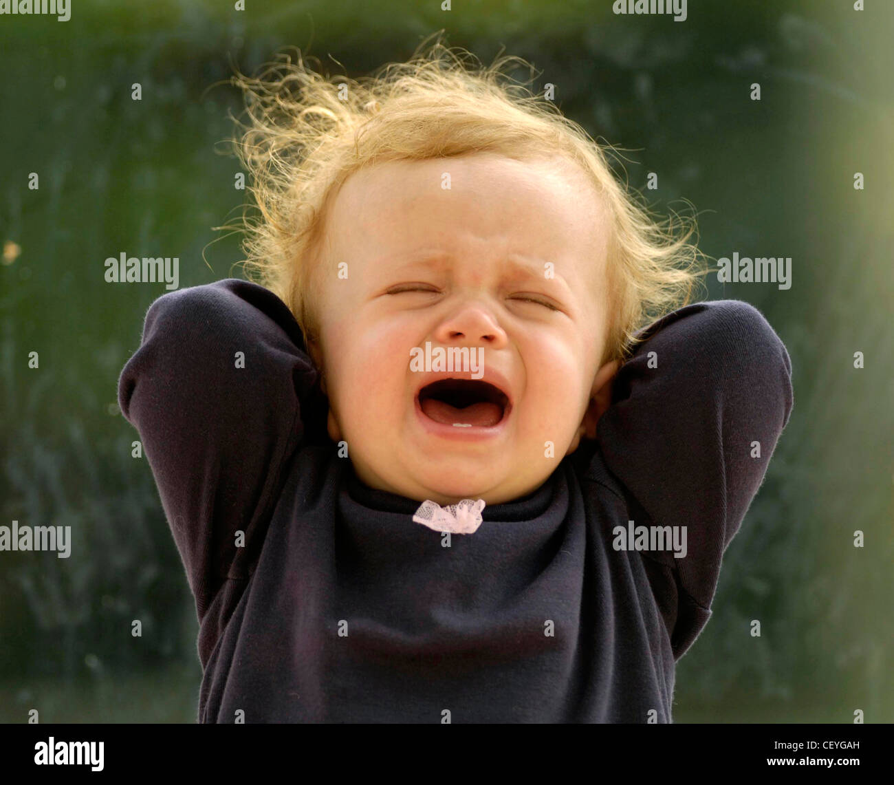 Female child with curly red hair, wearing a navy jumper, crying with ...