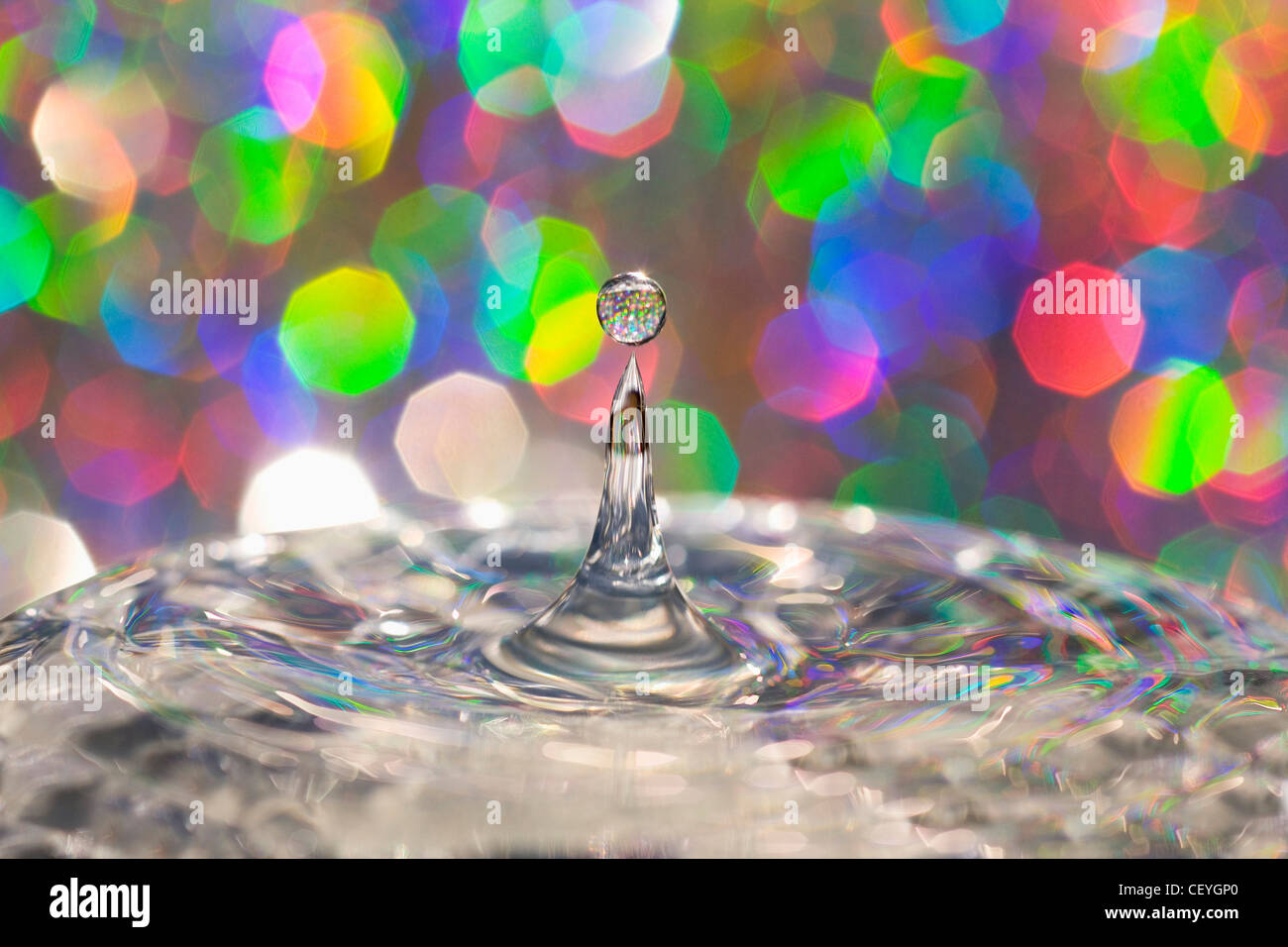 water droplet dropping to the surface of water with colourful lights in ...