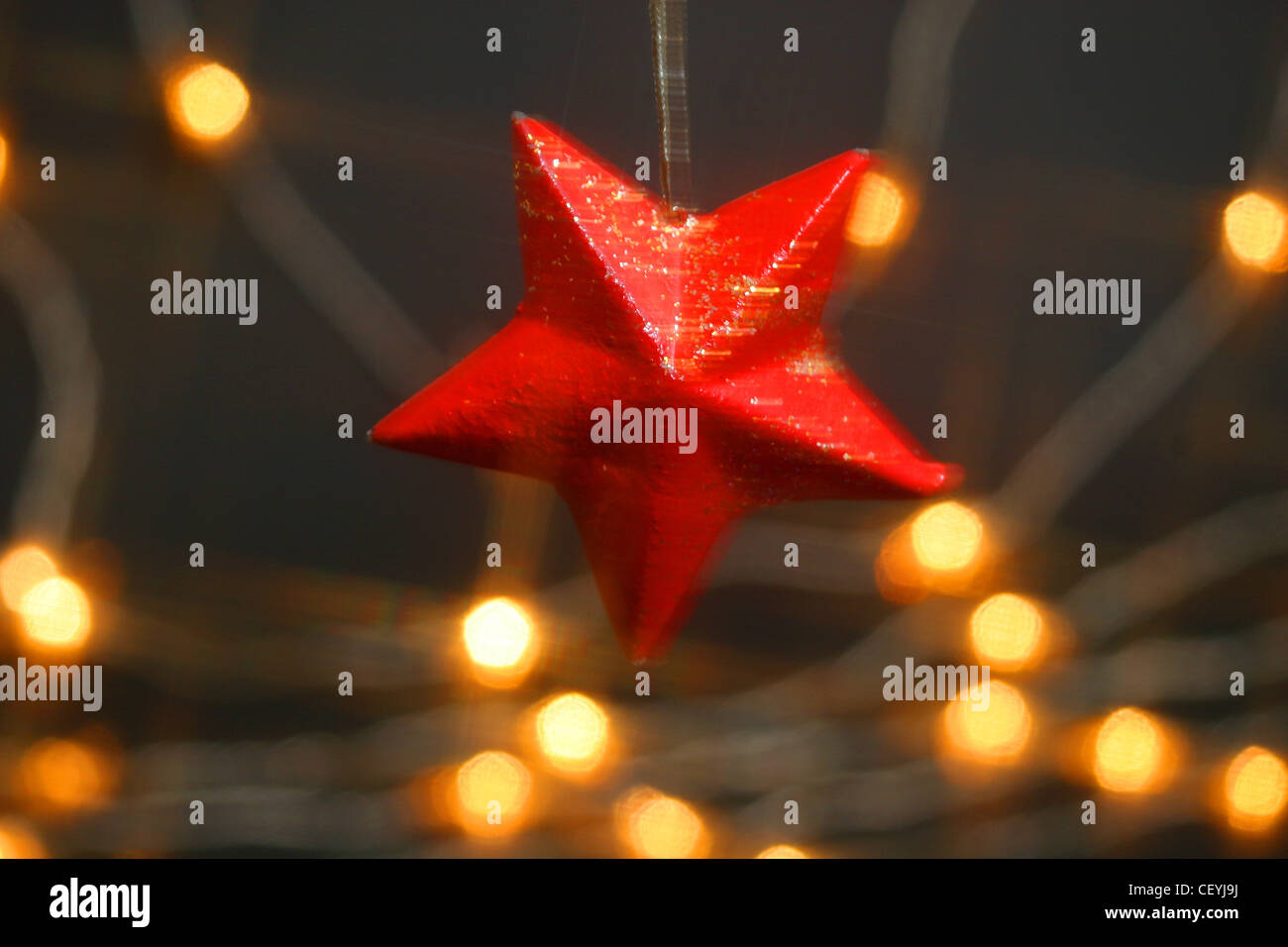A red metallic star christmas tree decoration hanging infront of some ...