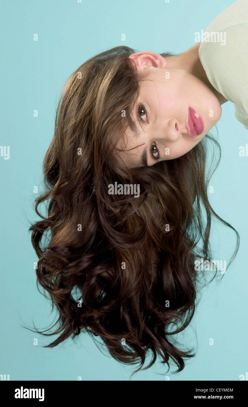 Female with long brunette curly hair wearing pale green top leaning ...