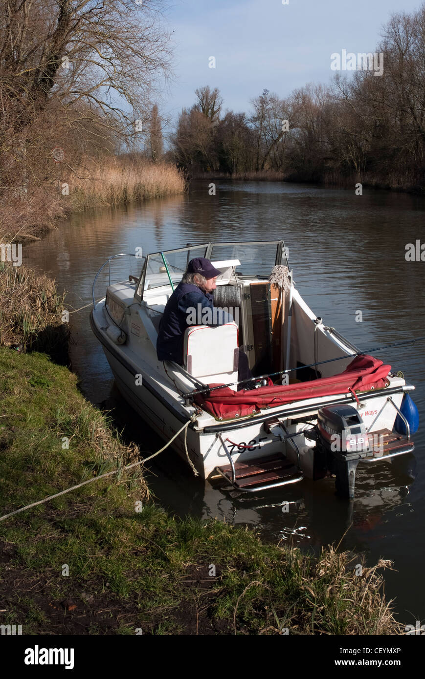 older man sitting fishing from small micro-cruiser on river waveney at ...