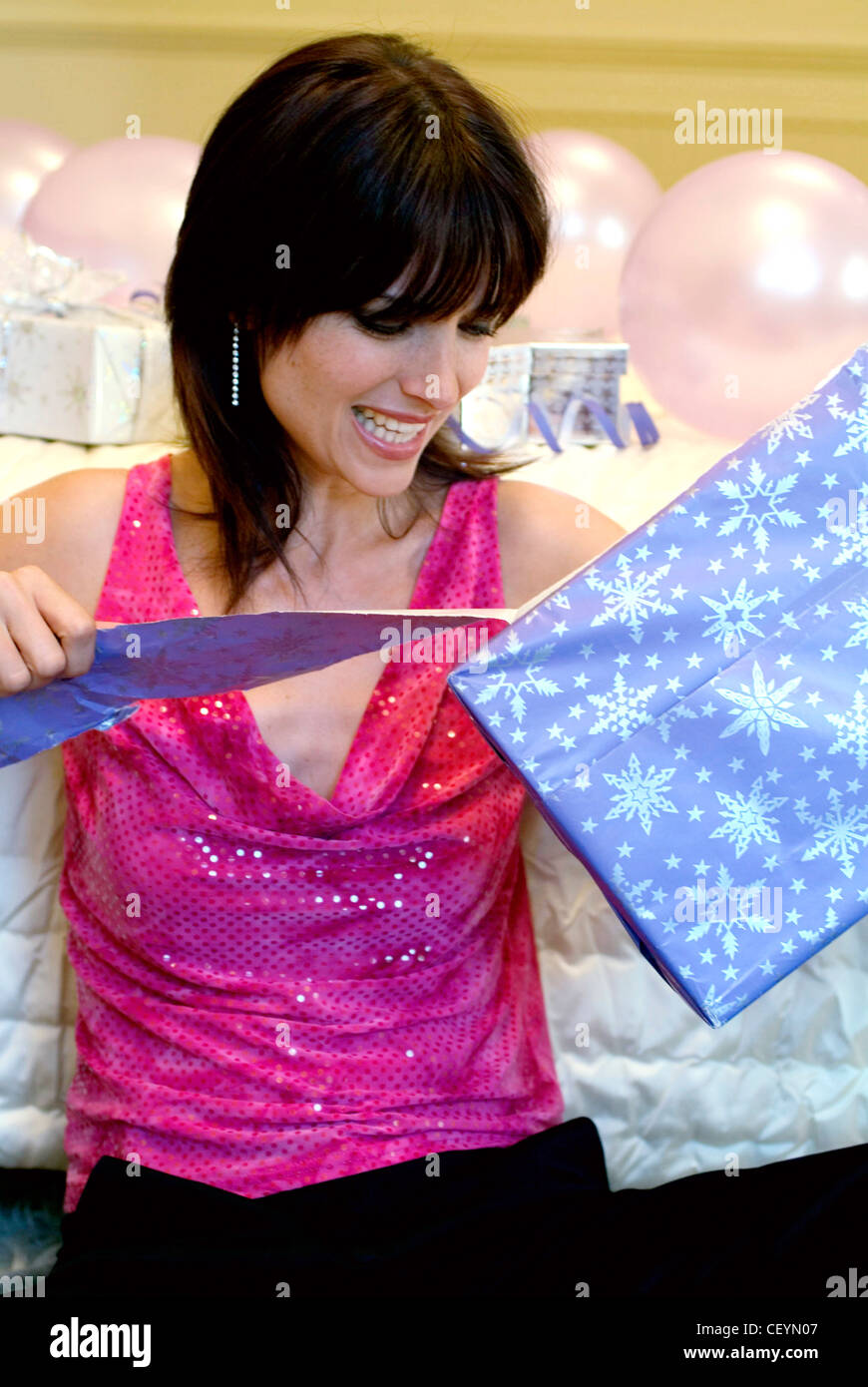 Female brunette hair wearing pink sequinned top, ripping paper off ...