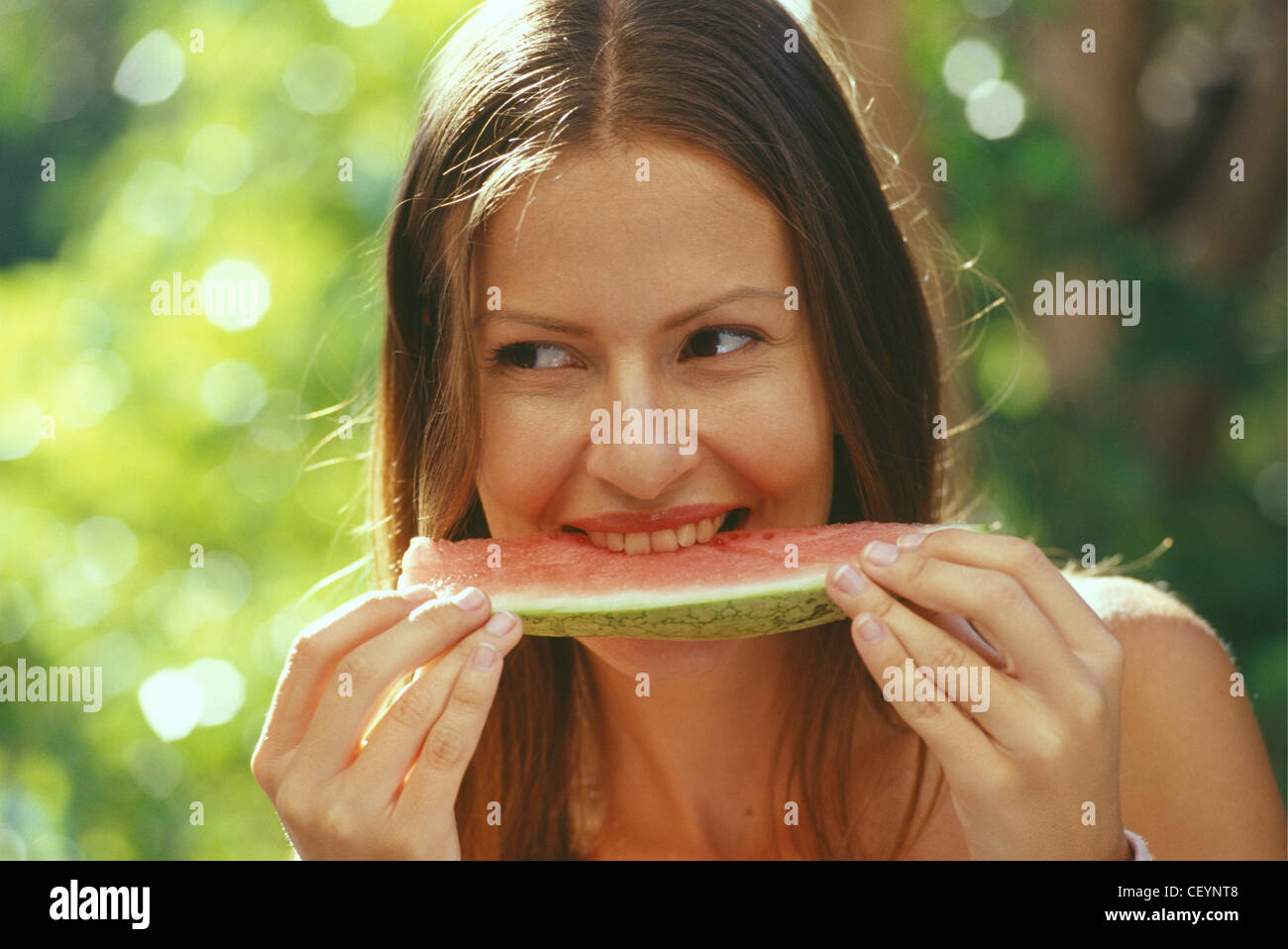 Brunette female straight centre parting hair and glossy lips, eating a ...