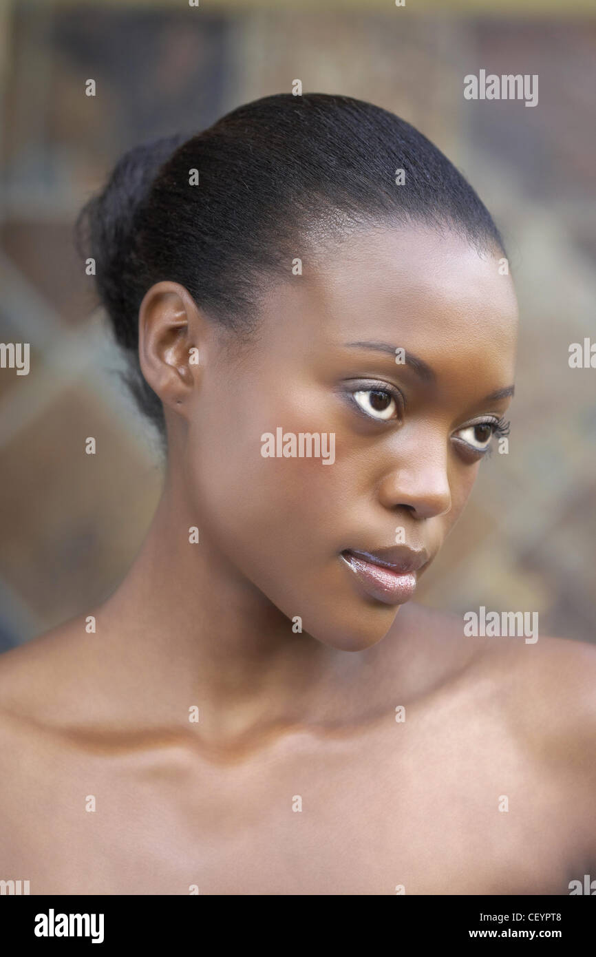 Female with hair scraped back into a bun, bare shoulders and looking ...