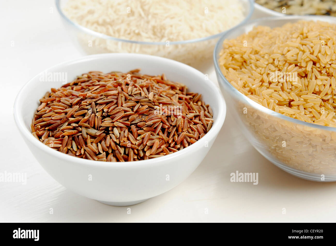 Four bowls of different varieties of rice with a bowl of red rice in ...