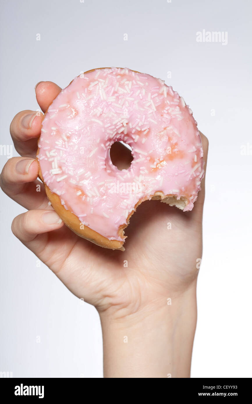 Close up image of female's hand holding a pink doughnut Stock Photo - Alamy