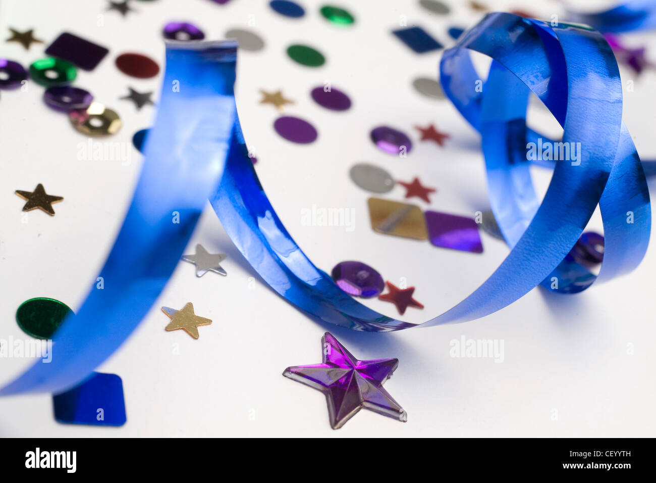 A still life image of colourful confetti and blue streamer on white ...