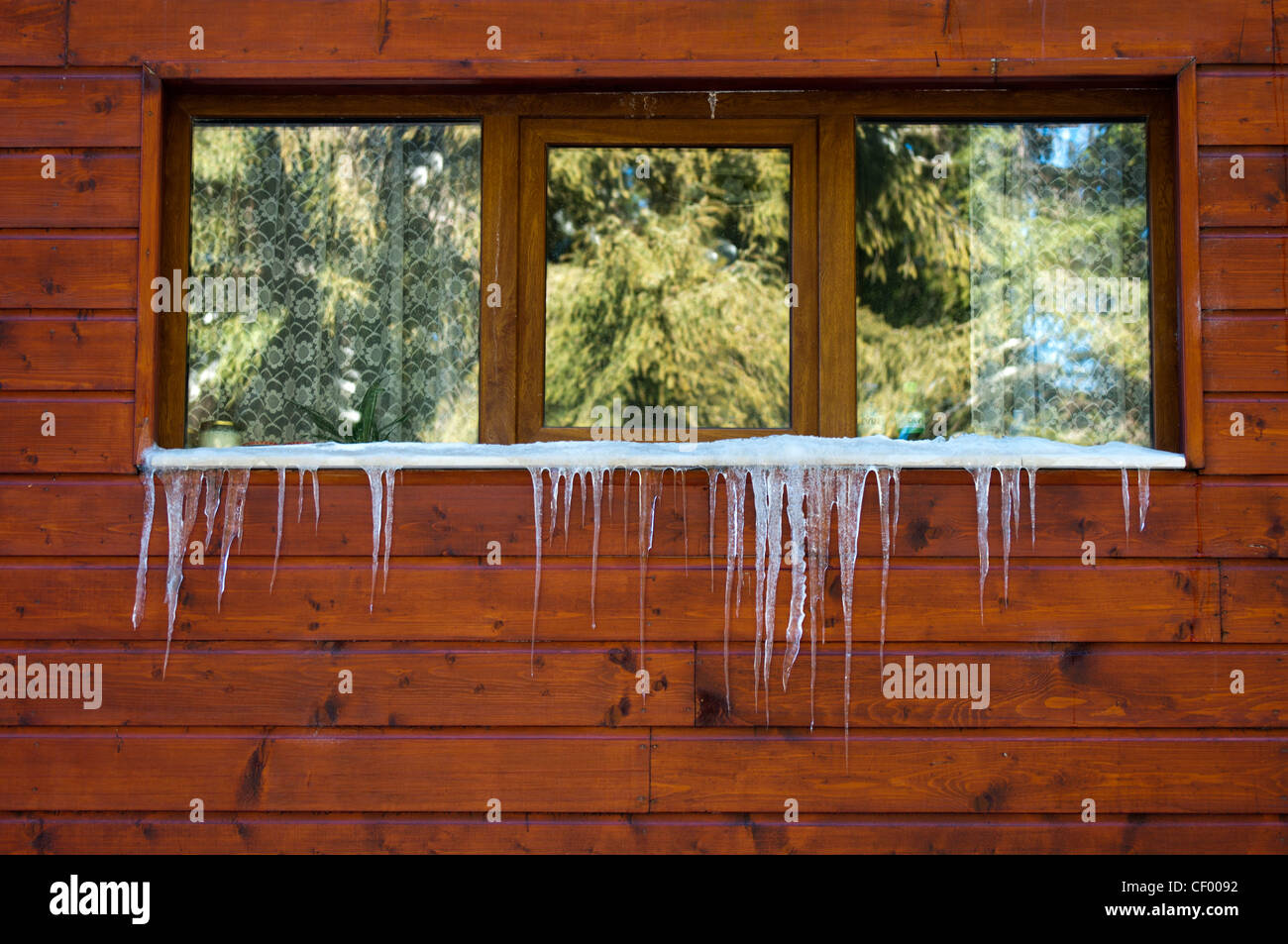 Icicles on window. Wooden house windows Stock Photo - Alamy