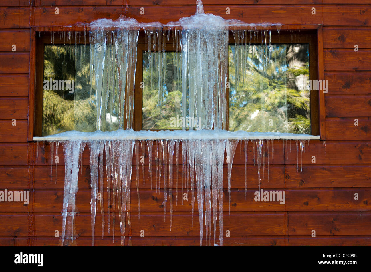 Icicles on window. Wooden house windows Stock Photo - Alamy