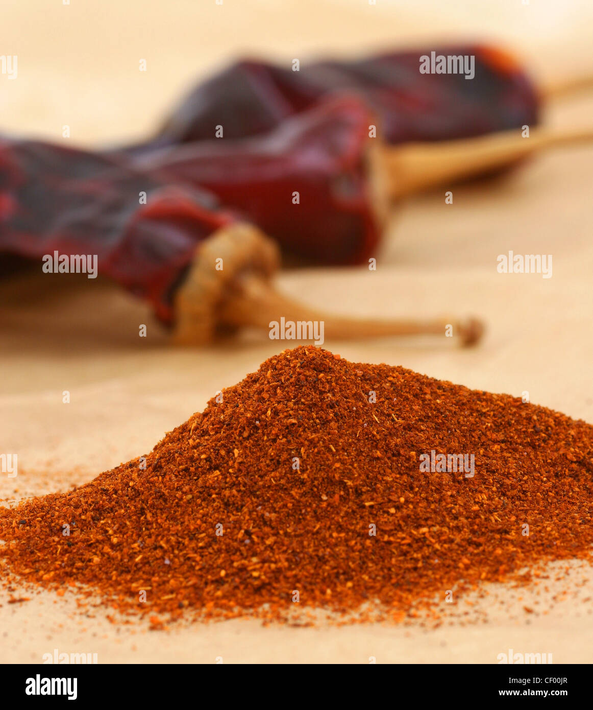 A small pile of ground chili powder with dried whole chilies in the ...