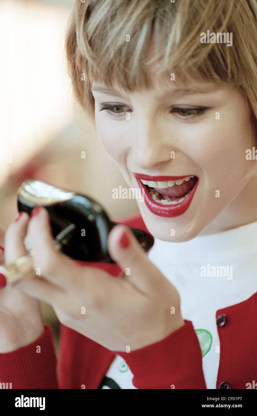 Female short fair hair, wearing a white top and red cardigan, holding a ...