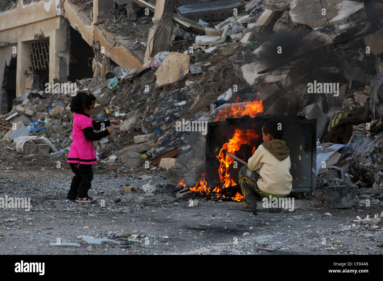 Children play with fire by ruins in the former Gaddafi compound of Bab ...