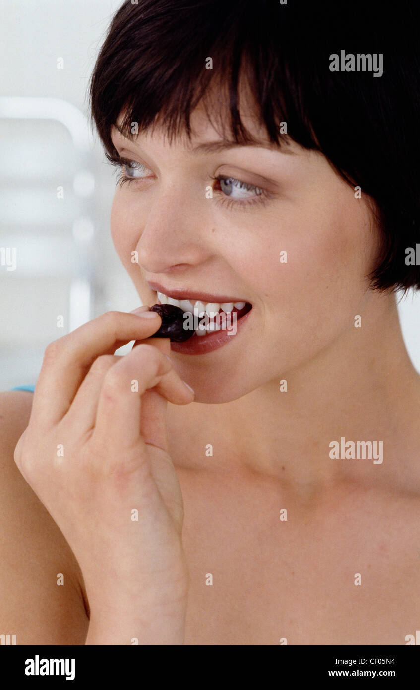 A Female smiling looking to the left eating a prune Stock Photo - Alamy