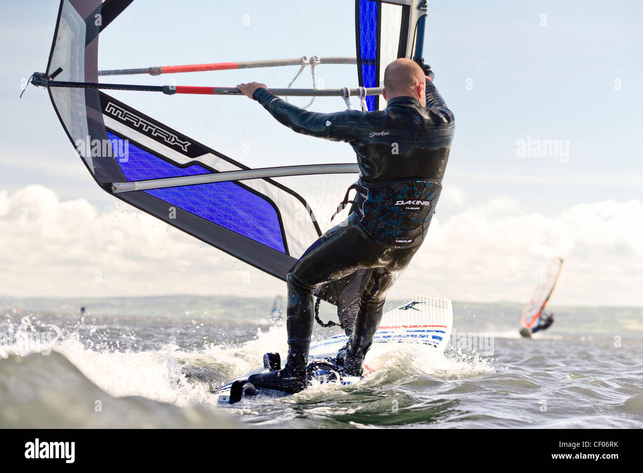 a windsurfer surfs away from the camera towards the horizon Stock Photo ...
