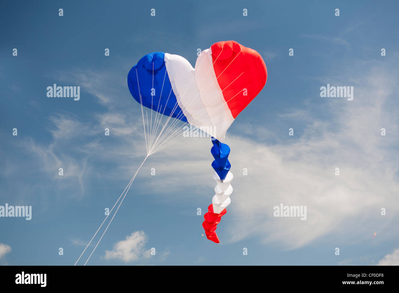 heart shape kite in red white and blue flies high into the blue sky ...