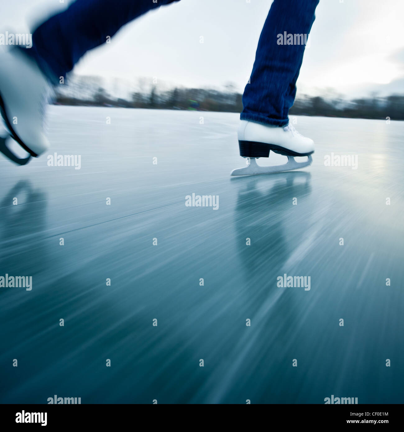 Young woman ice skating outdoors on a pond on a freezing winter day ...
