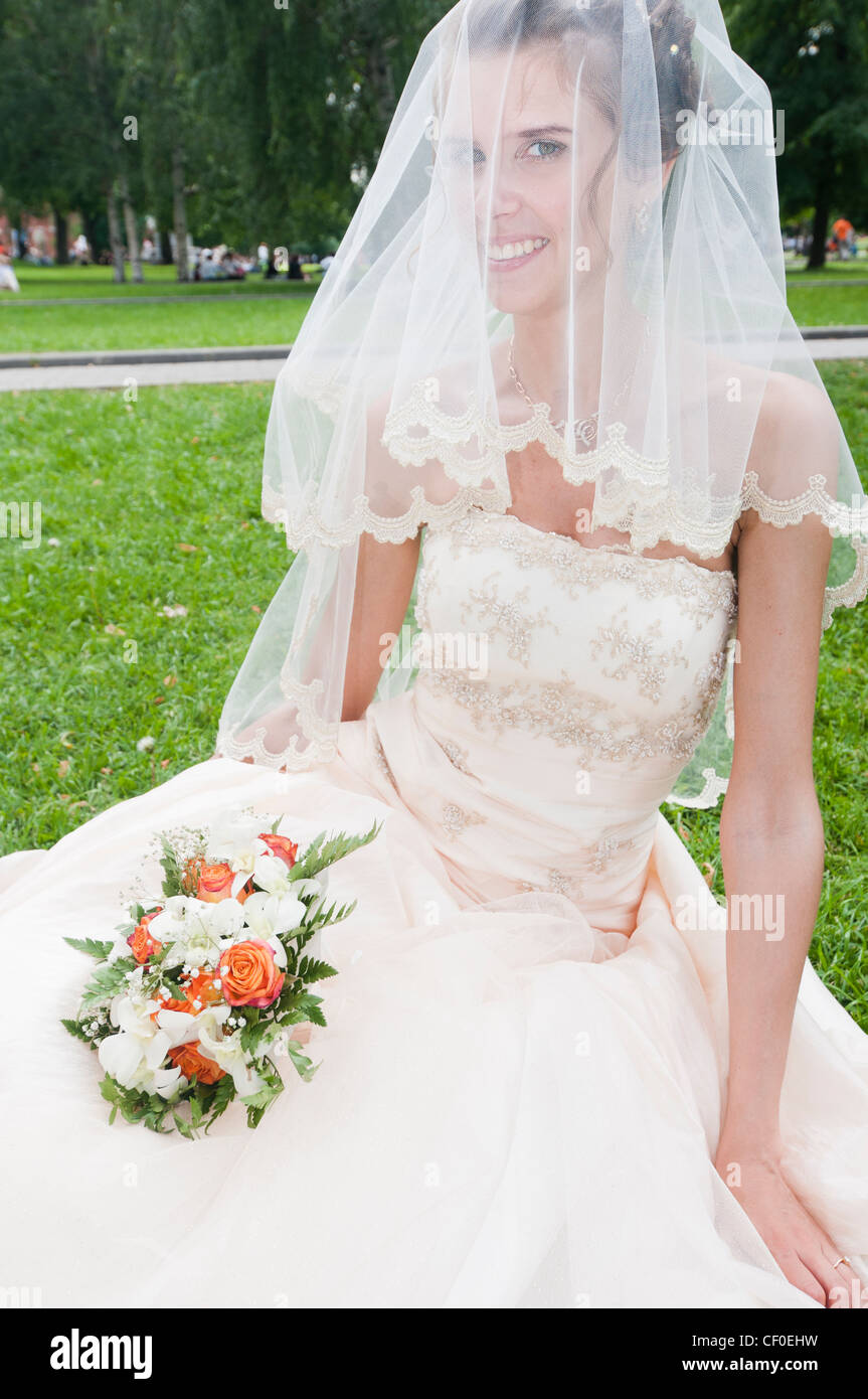 Beautiful young bride in green park Stock Photo - Alamy