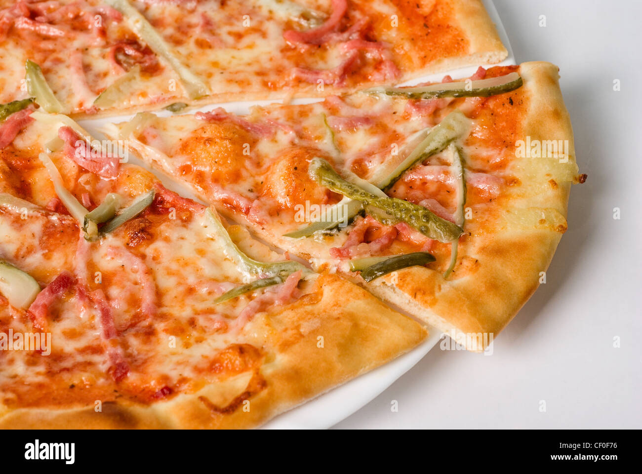 pizza closeup with boiled sausage, ham, marinated gherkin and ...